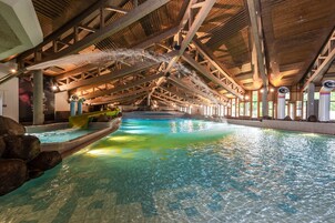 Piscina interna com teto de madeira e águas cristalinas.
