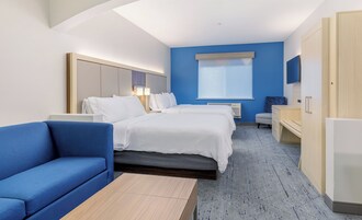 Quarto de hotel com uma cama, um sofá azul, uma escrivaninha e um guarda-roupa.