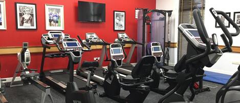 Uma academia com esteiras, elípticos e aparelhos de musculação.