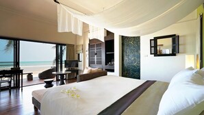 Um quarto espaçoso com uma cama grande, um espaço de estar com vista para a praia e uma televisão.