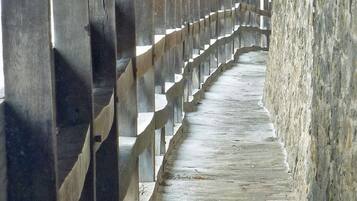 Um corredor com balaústres de madeira e paredes de pedra.