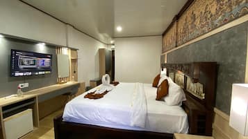 Quarto de hotel com cama, escrivaninha, televisão e obra de arte na parede.