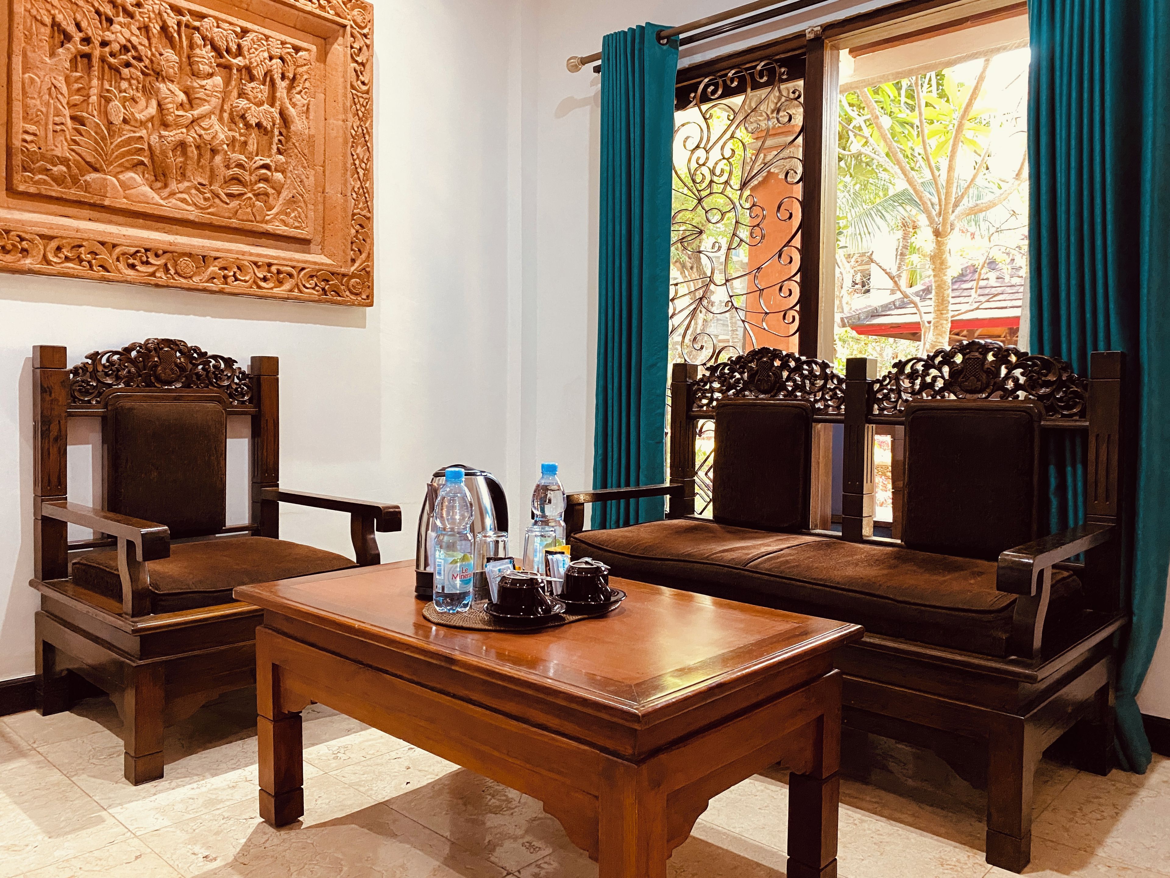 Quarto com sofá de madeira, mesa de centro e um detalhe decorativo na parede.