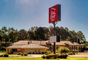 Um Red Roof Inn com um edifício de dois andares, estacionamento e céu claro.