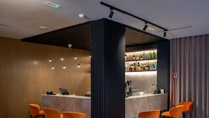 Uma área de bar com balcão, banquetas e uma variedade de garrafas.