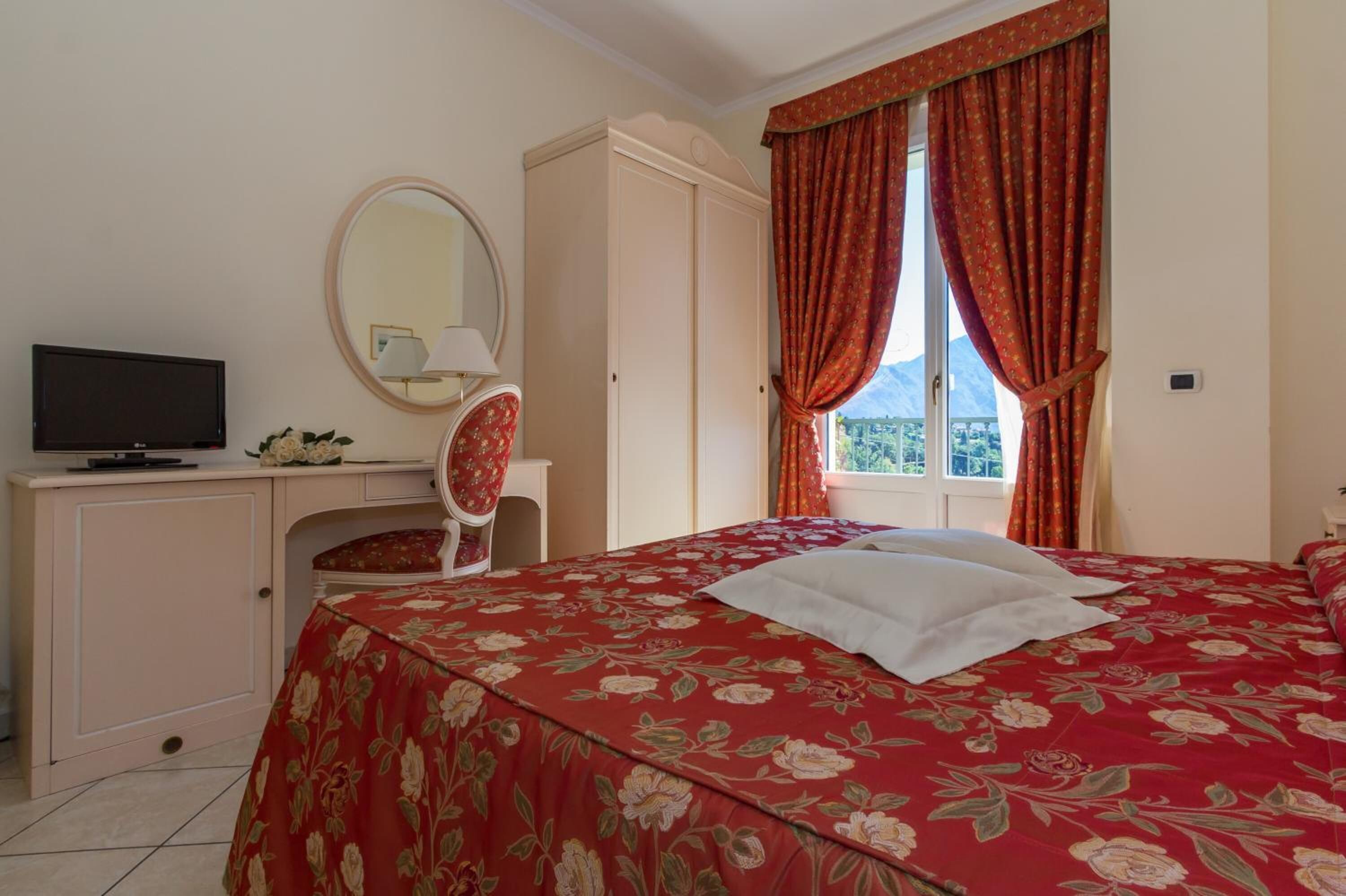 Quarto com cama, escrivaninha, cadeira, guarda-roupa e televisão.