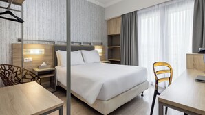 Quarto de hotel com uma cama grande, mesas de cabeceira, uma escrivaninha e uma cadeira.