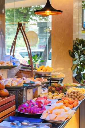 Buffet com diversas frutas e pastelaria.