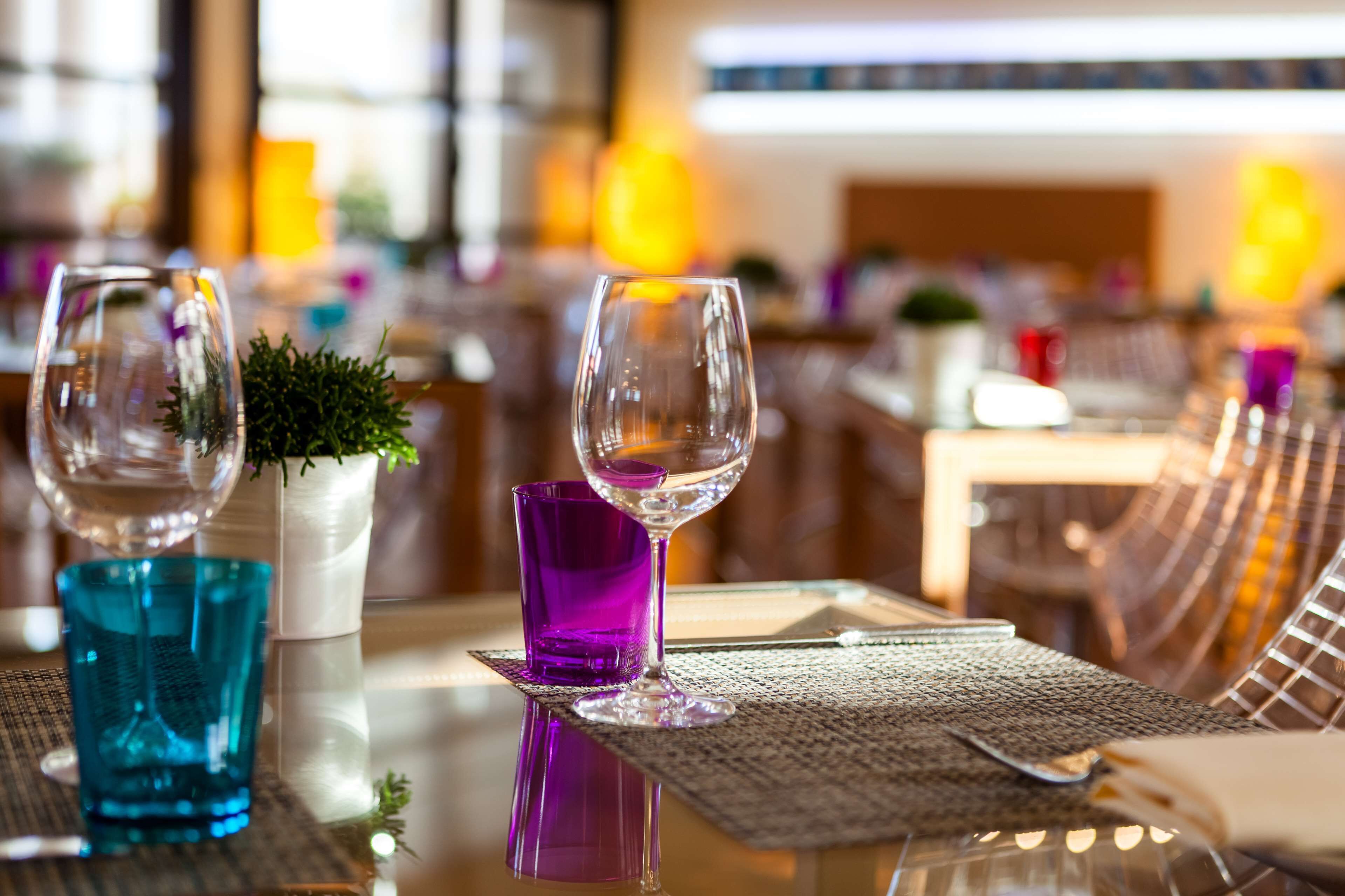 Uma mesa de jantar com um copo de água, um copo roxo e uma taça de vinho.