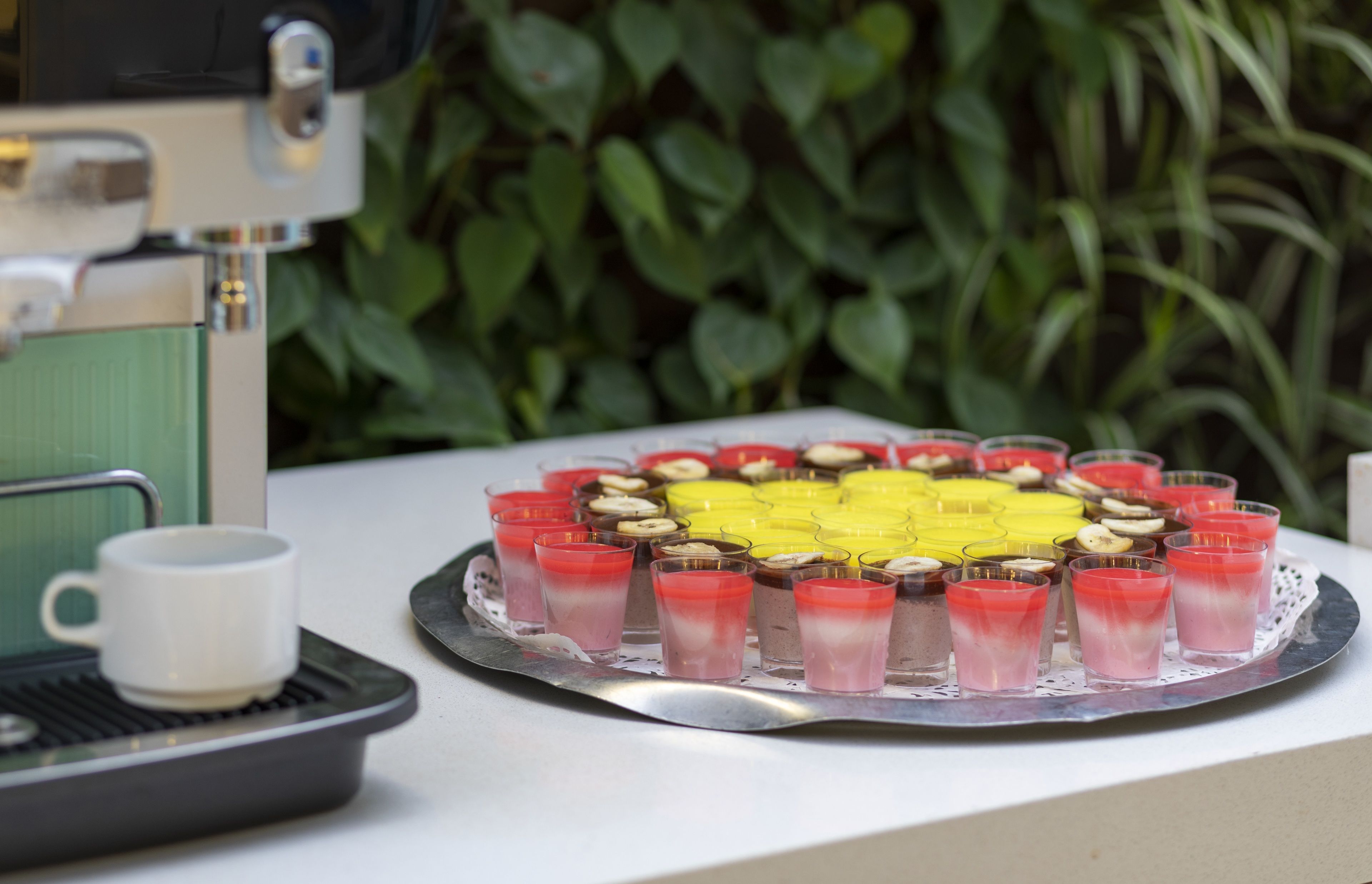Uma bandeja com bebidas coloridas e uma máquina de café sobre uma mesa.