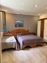 Quarto com duas camas, cabeceira de madeira, quadro emoldurado na parede e um guarda-roupa.