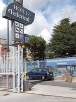 Placa de hotel com ícones de comodidades, placa de estacionamento e placa com o nome de uma universidade.