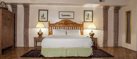 Quarto com uma cama grande, duas mesas de cabeceira com luminárias, um guarda-roupa de madeira e uma cabeceira decorativa.