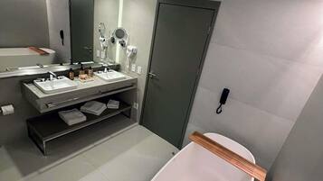 Uma casa de banho moderna com lavatório, espelho, secador de cabelo e banheira.