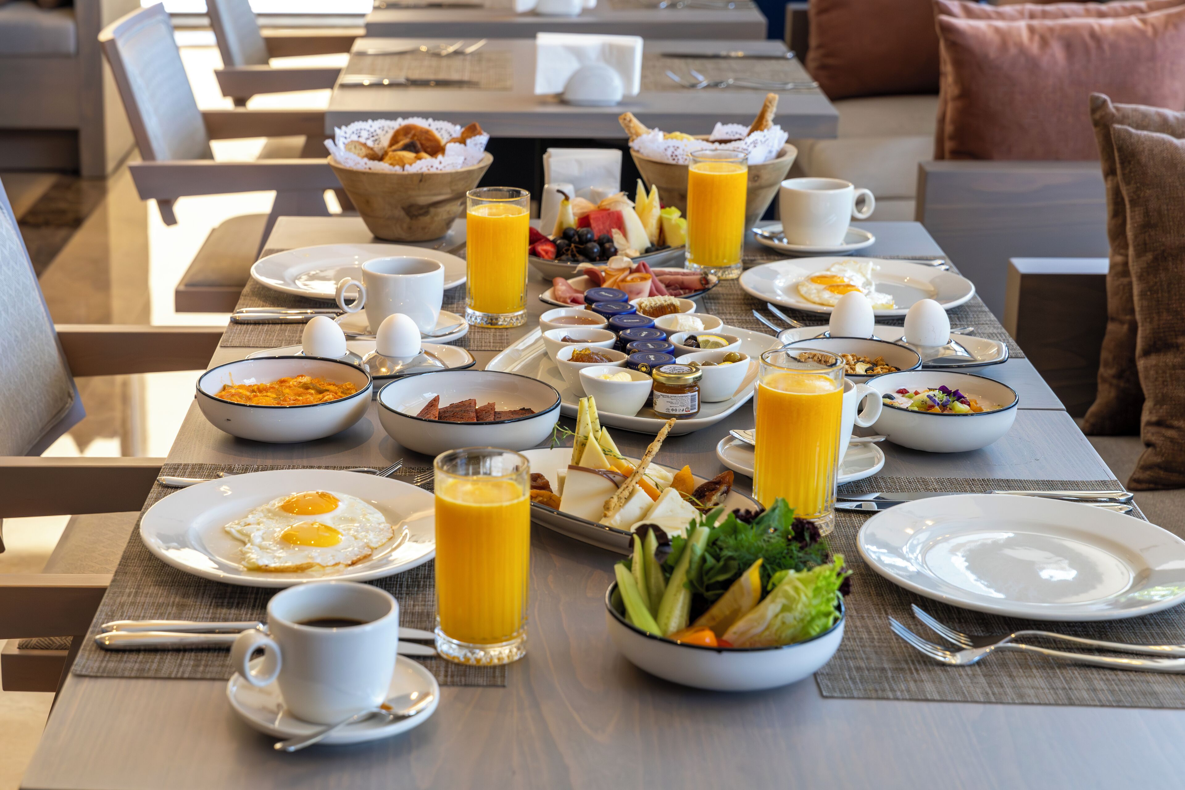 Um buffet de café da manhã com diversos pratos, incluindo ovos, frutas e sucos.