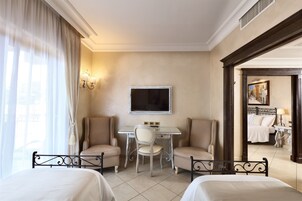 Quarto de hotel com duas camas, uma mesa, uma cadeira e uma televisão.