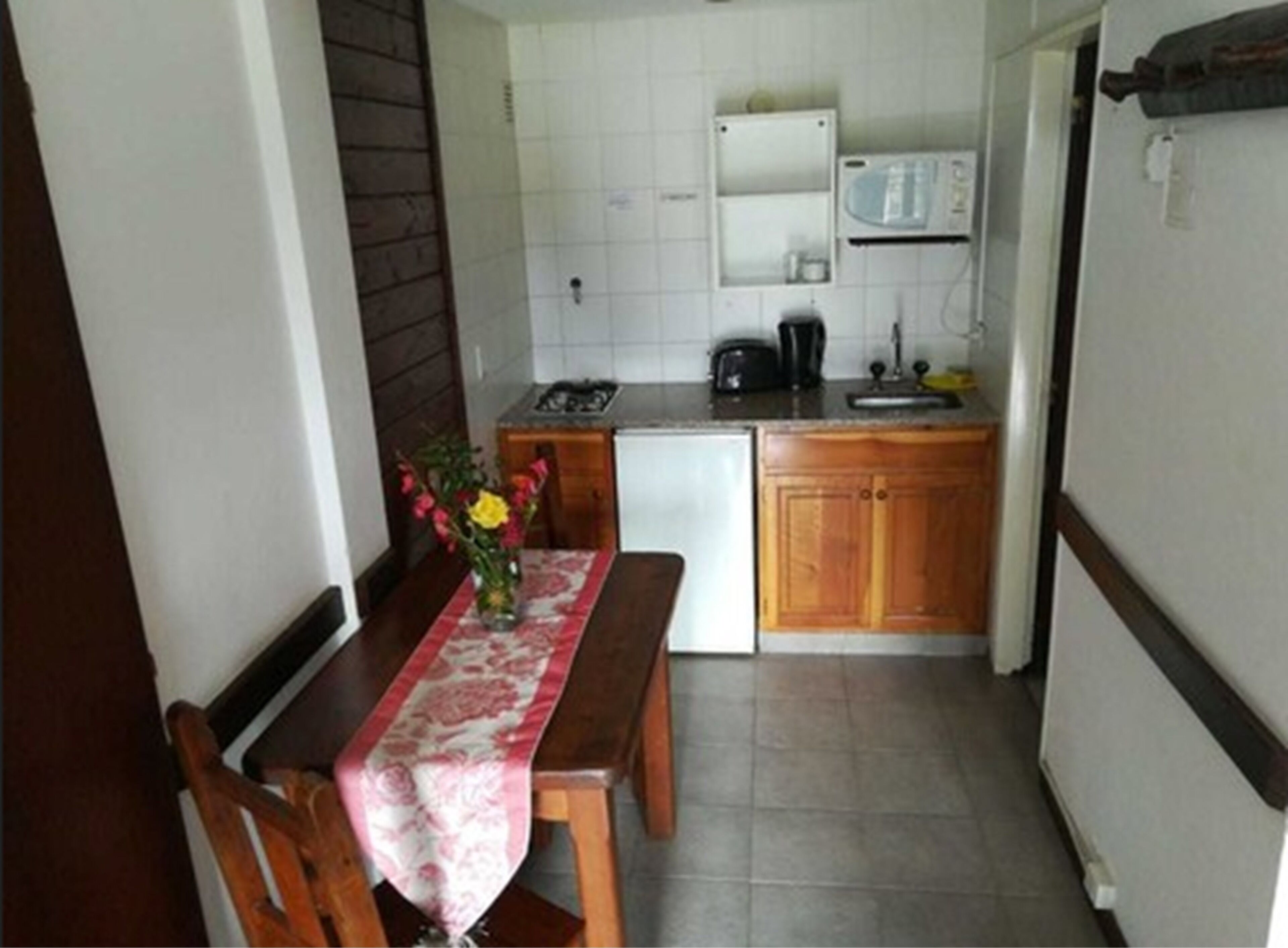 Uma cozinha pequena com uma mesa de jantar, cadeiras e um vaso de flores.