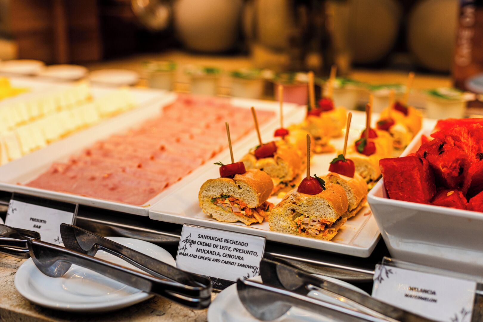 Buffet com diversas opções de comida, incluindo sanduíches, carnes e legumes.