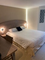 Quarto de hotel com uma cama, mesa de cabeceira e uma cadeira.