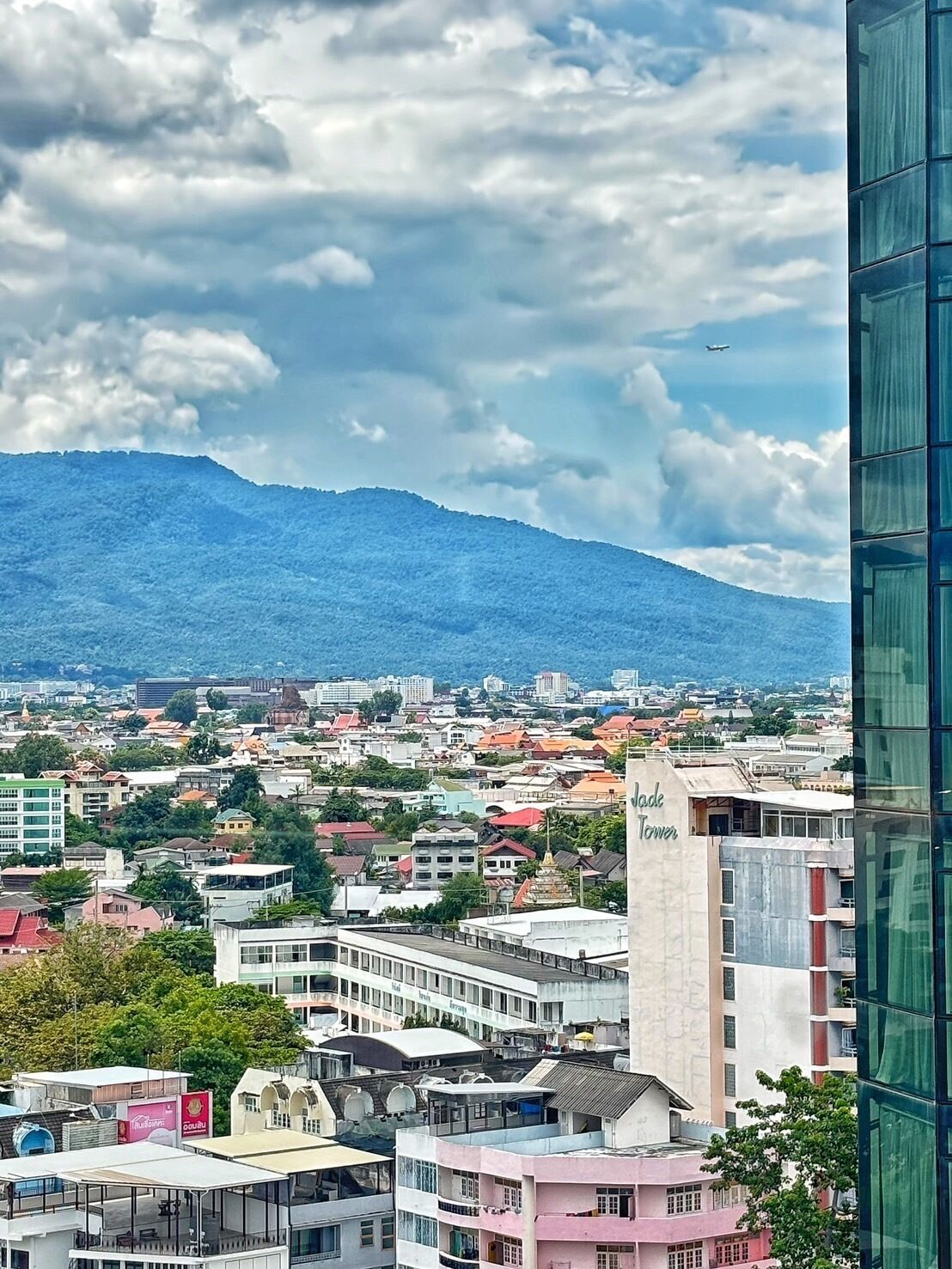 Paisagem urbana com uma montanha imponente ao fundo, vários edifícios e céu claro.