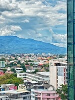 Paisagem urbana com uma montanha imponente ao fundo, vários edifícios e céu claro.