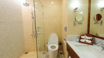 Casa de banho moderna com cabine de duche em vidro, sanita e lavatório com bancada de mármore.