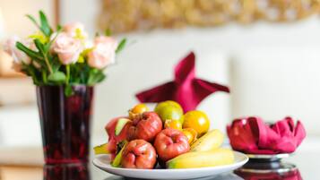 Uma mesa com uma travessa de frutas e um vaso de flores.