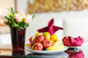Uma mesa com uma travessa de frutas e um vaso de flores.
