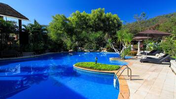 Piscina com deck revestido, espreguiçadeiras e um gazebo.
