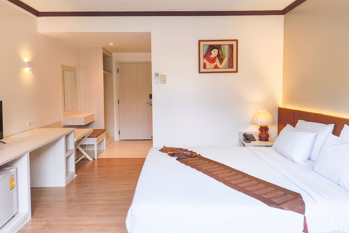 Quarto de hotel com cama, mesa de cabeceira, abajur e um quadro na parede.