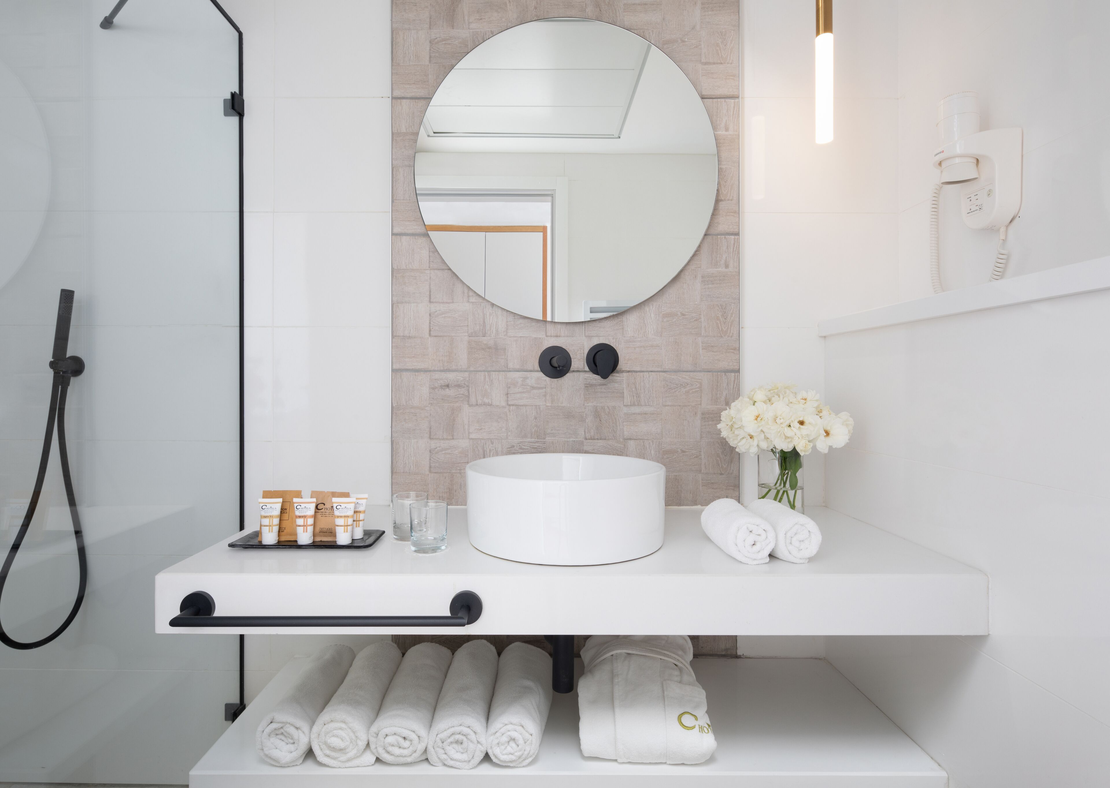 Uma casa de banho moderna com uma pia branca, espelho e porta-toalhas.