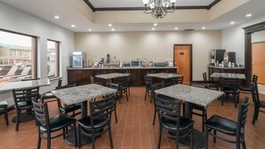 Um restaurante com mesas, cadeiras, área de cozinha e vista através de grandes janelas.