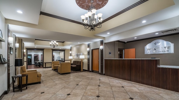 Um hall de hotel com balcão de recepção, área de estar e um candelabro.