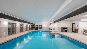 Piscina interna com água cristalina, rodeada por paredes com janelas e portas.