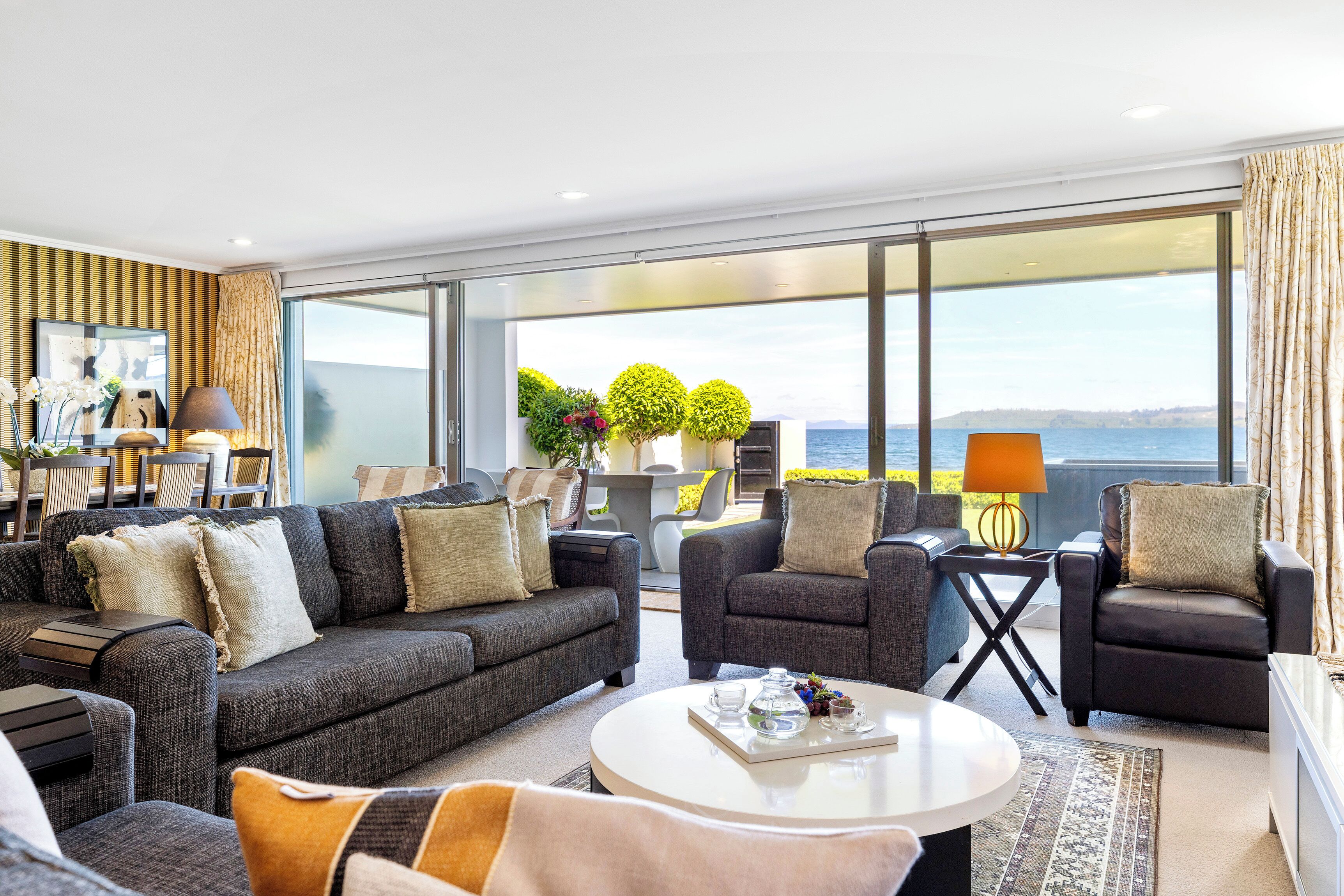 Uma sala de estar moderna com sofá, mesa de centro e vista para o mar.