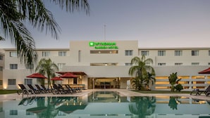 Um hotel Wyndham Garden com piscina, espreguiçadeiras e palmeiras.