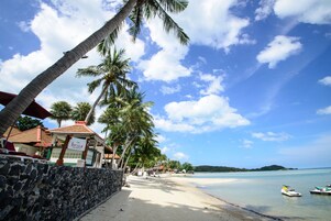 Na praia, praia de areia branca, espreguiçadeiras, guarda-sóis de praia 