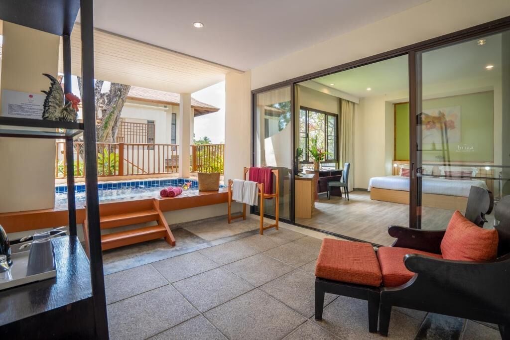 Quarto de hotel moderno com varanda, área de jantar e uma janela grande.