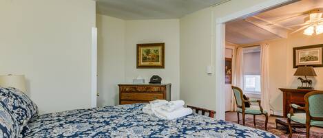 Quarto com uma cama grande, cômoda, cadeira e escrivaninha com abajur.