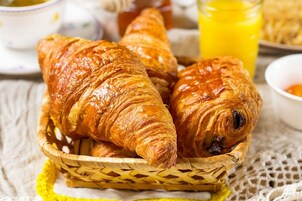 Uma cesta de croissants sobre uma mesa com um pano amarelo.