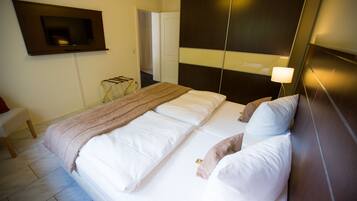 Quarto de hotel com cama, televisão presa na parede e abajur.
