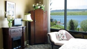 Quarto de hotel com vista para um lago, um armário de madeira, uma televisão e uma almofada florida.
