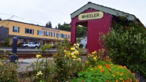 A red and yellow building labeled "WHEELER" with a train track in front.