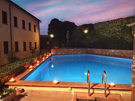 Piscina com borda de pedra e deck de tijolos.