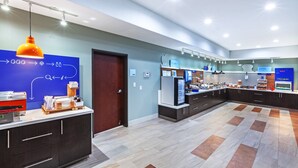 Um hall de hotel moderno com uma receção, uma área de café e uma apresentação de comida.
