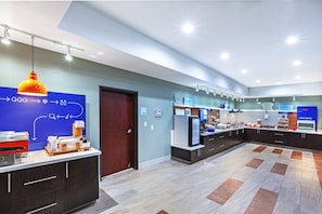 Um hall de hotel moderno com uma receção, uma área de café e uma apresentação de comida.