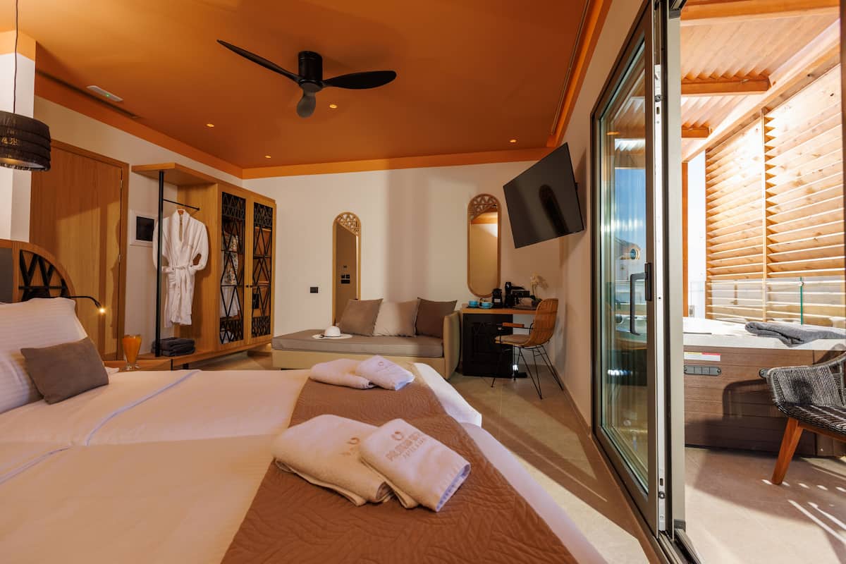 Quarto de hotel moderno com uma cama grande, uma escrivaninha, uma cadeira e uma televisão.