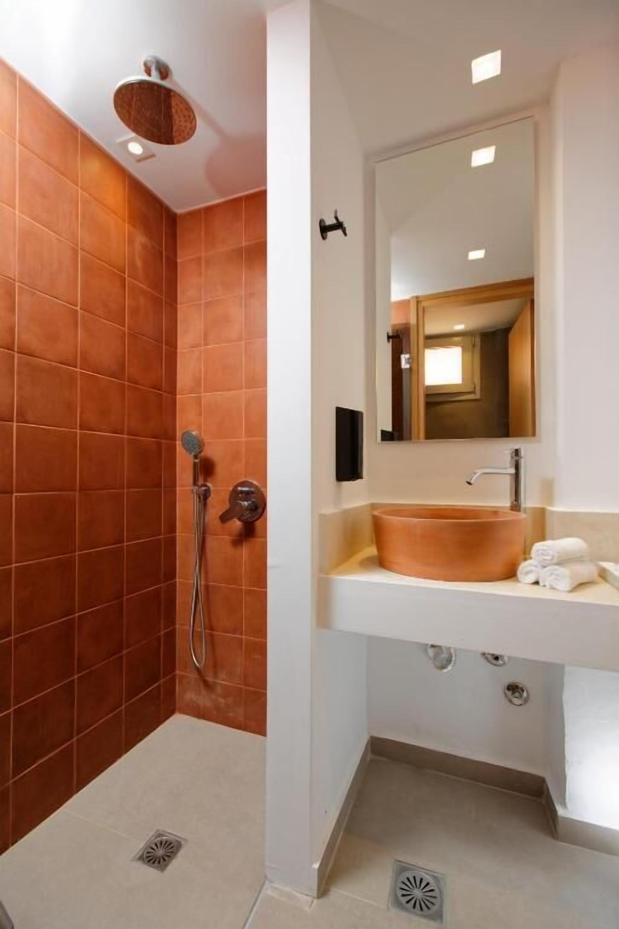 Casa de banho com zona de duche e lavatório com espelho.