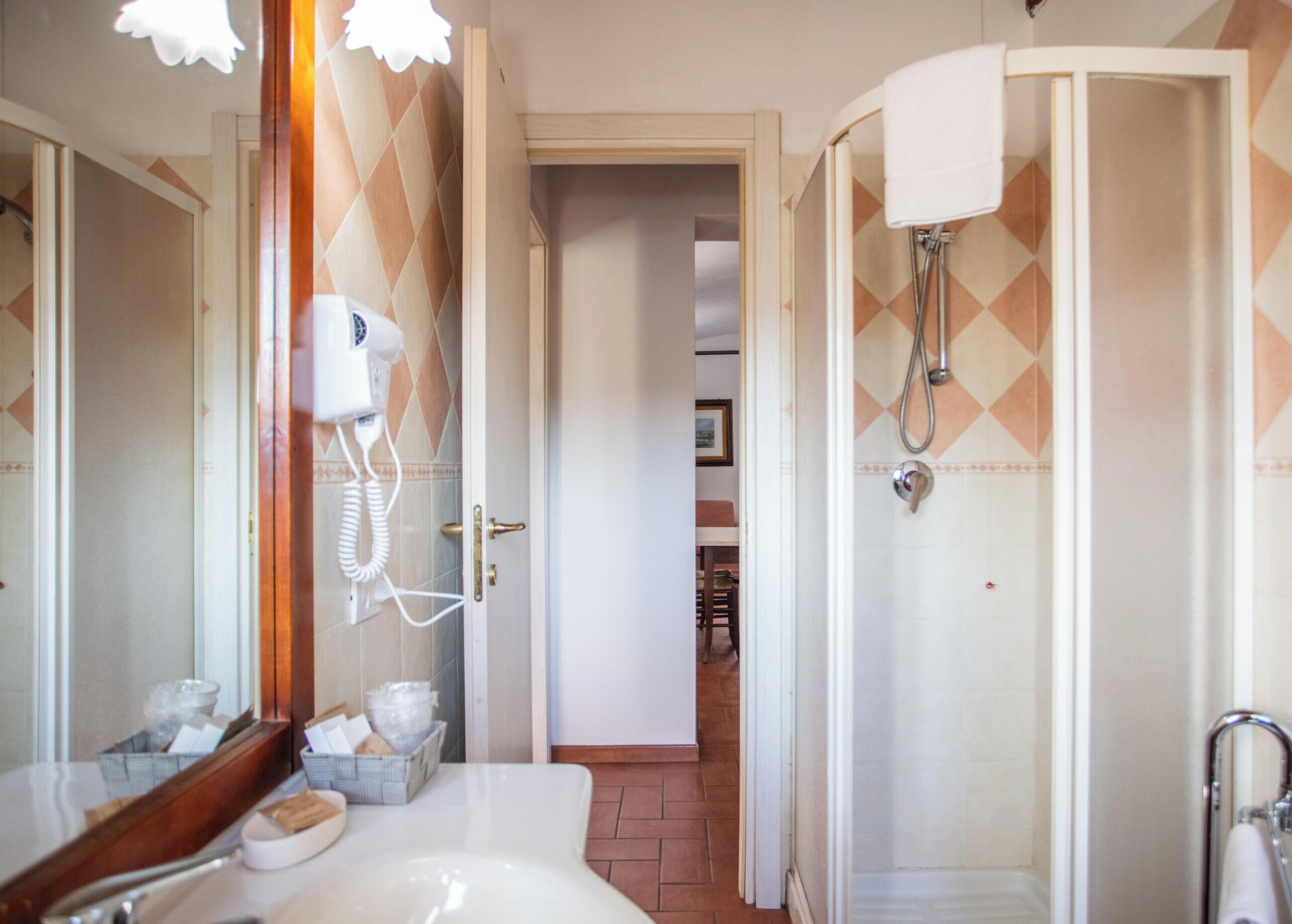 Casa de banho com lavatório, espelho, secador de cabelo e chuveiro.