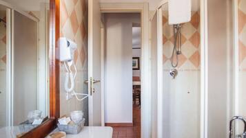 Casa de banho com lavatório, espelho, secador de cabelo e chuveiro.